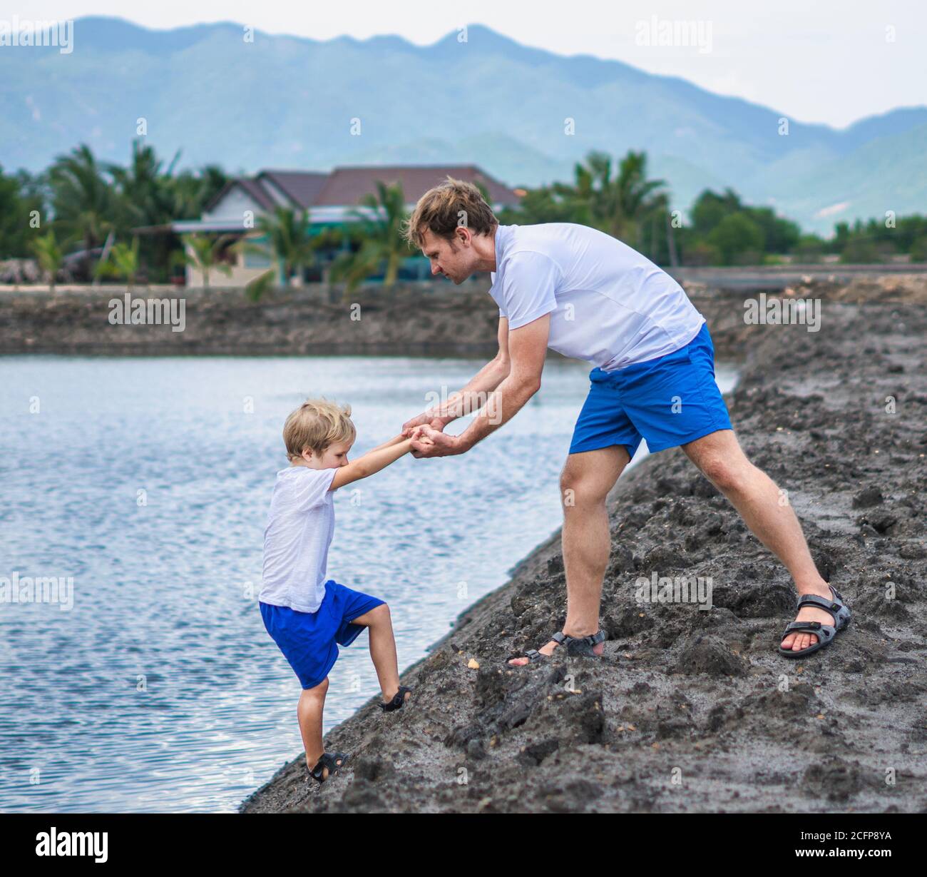 Dad helps son go down to lake water, explains safety rules. Family ...