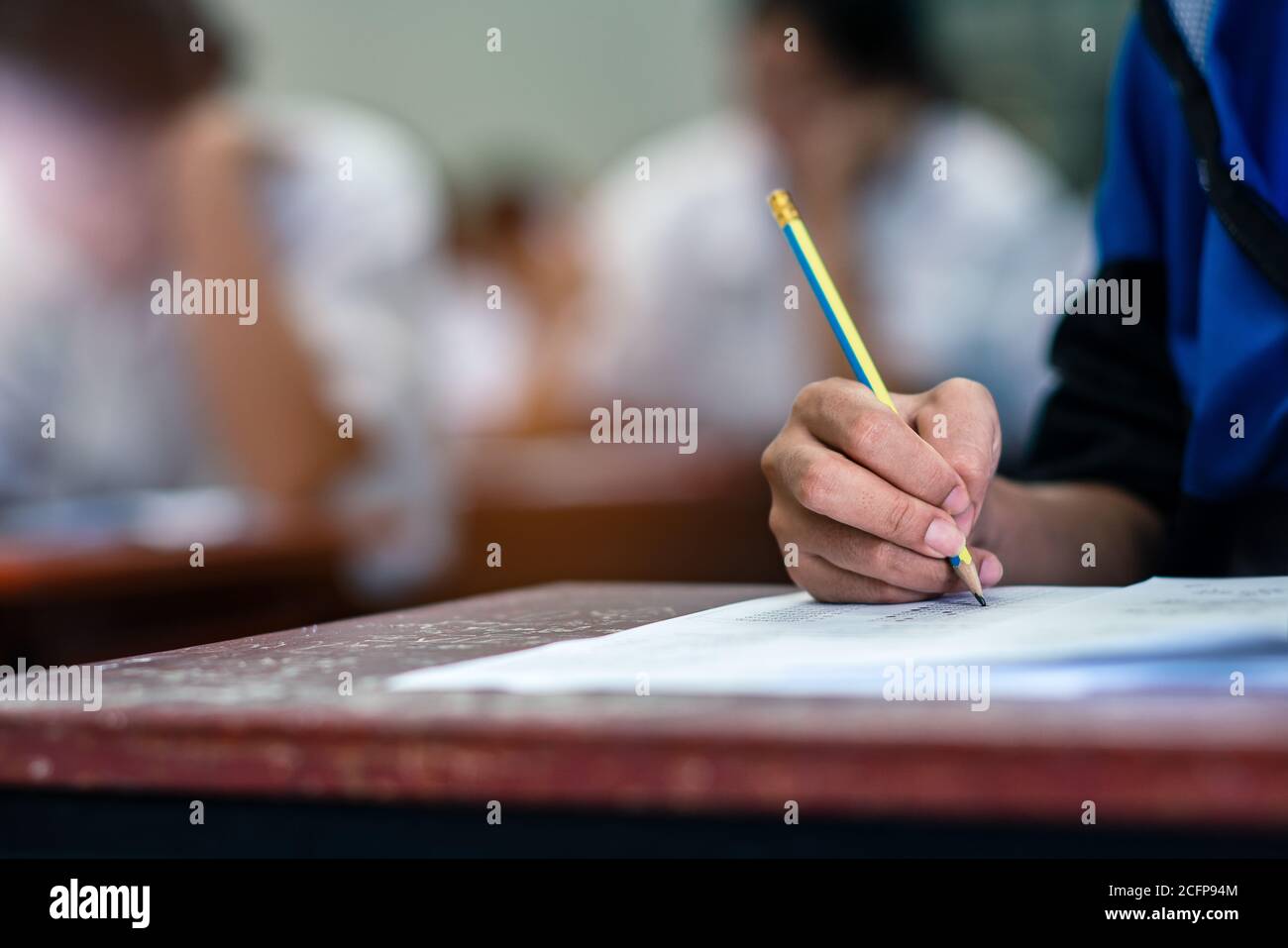 Students writing and reading exam answer sheets exercises in classroom ...