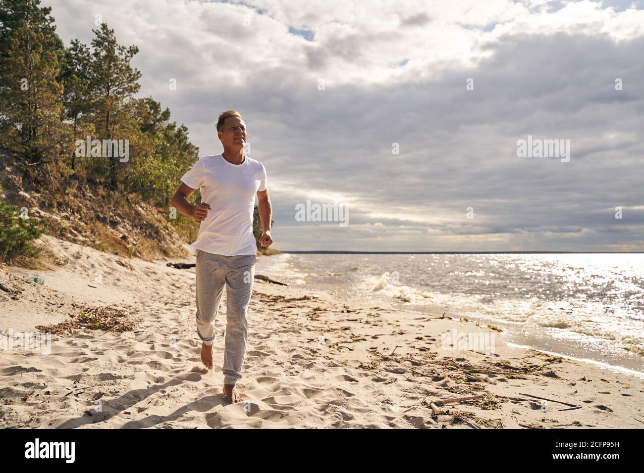 Happy male running alone along sea shore Stock Photo - Alamy