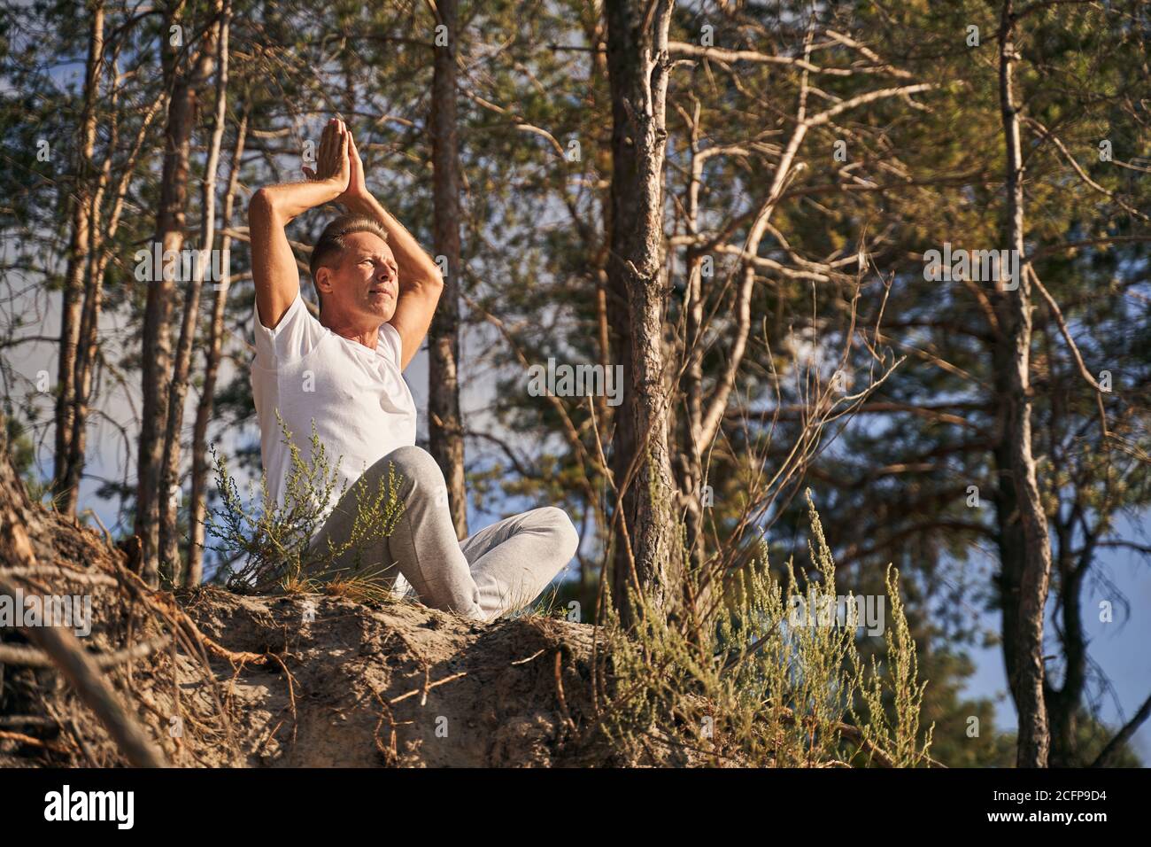 Smiling sporty man meditating alone in wood Stock Photo - Alamy