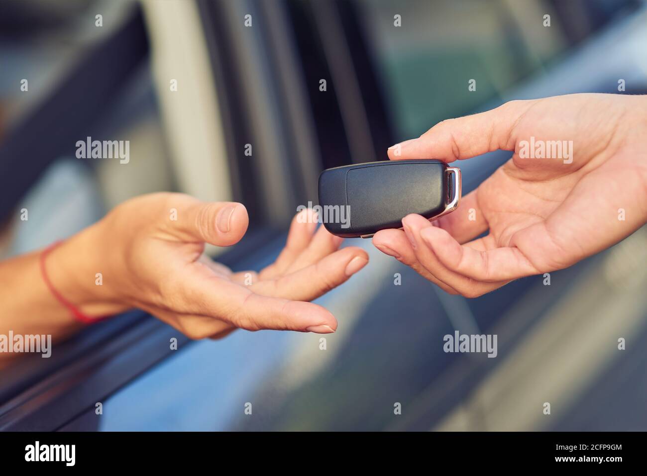 Car purchase concept. Close up shot of a male hand giving a car keys to ...