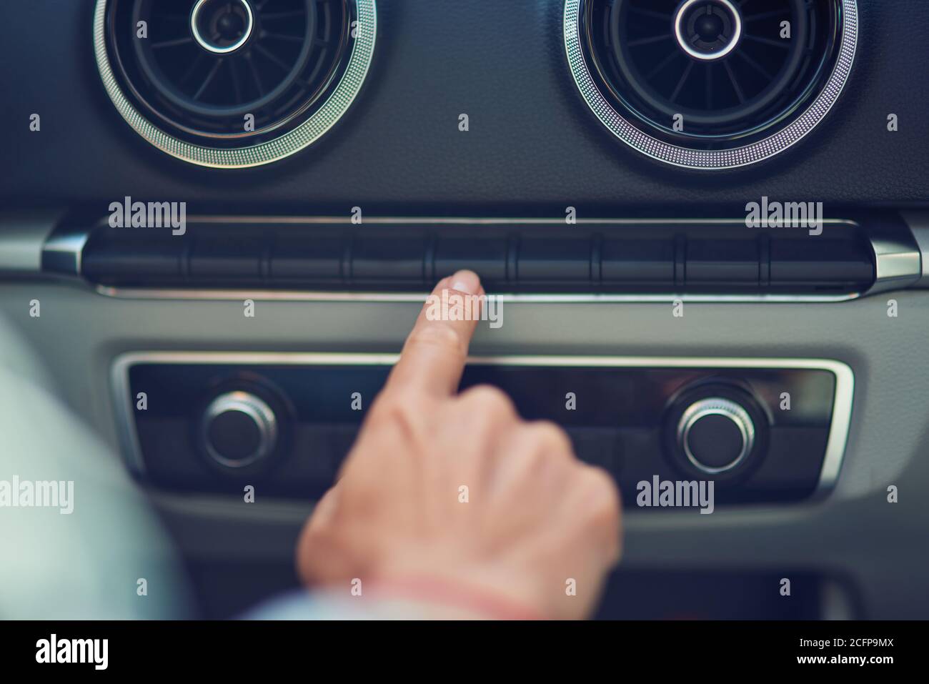Cropped shot of a woman pushing the button on the car dashboard while ...