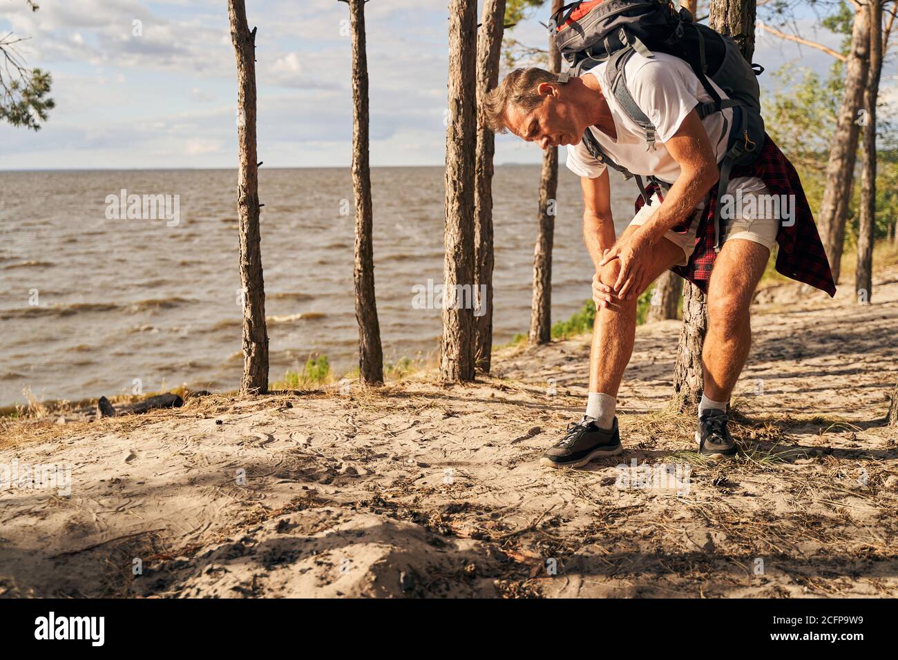 Man feeling injury in leg during walk in nature Stock Photo - Alamy