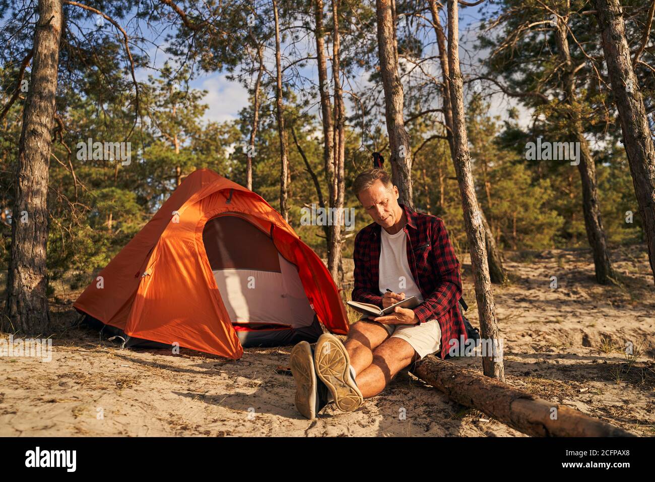 Man writing in notepad while having rest in forest Stock Photo - Alamy