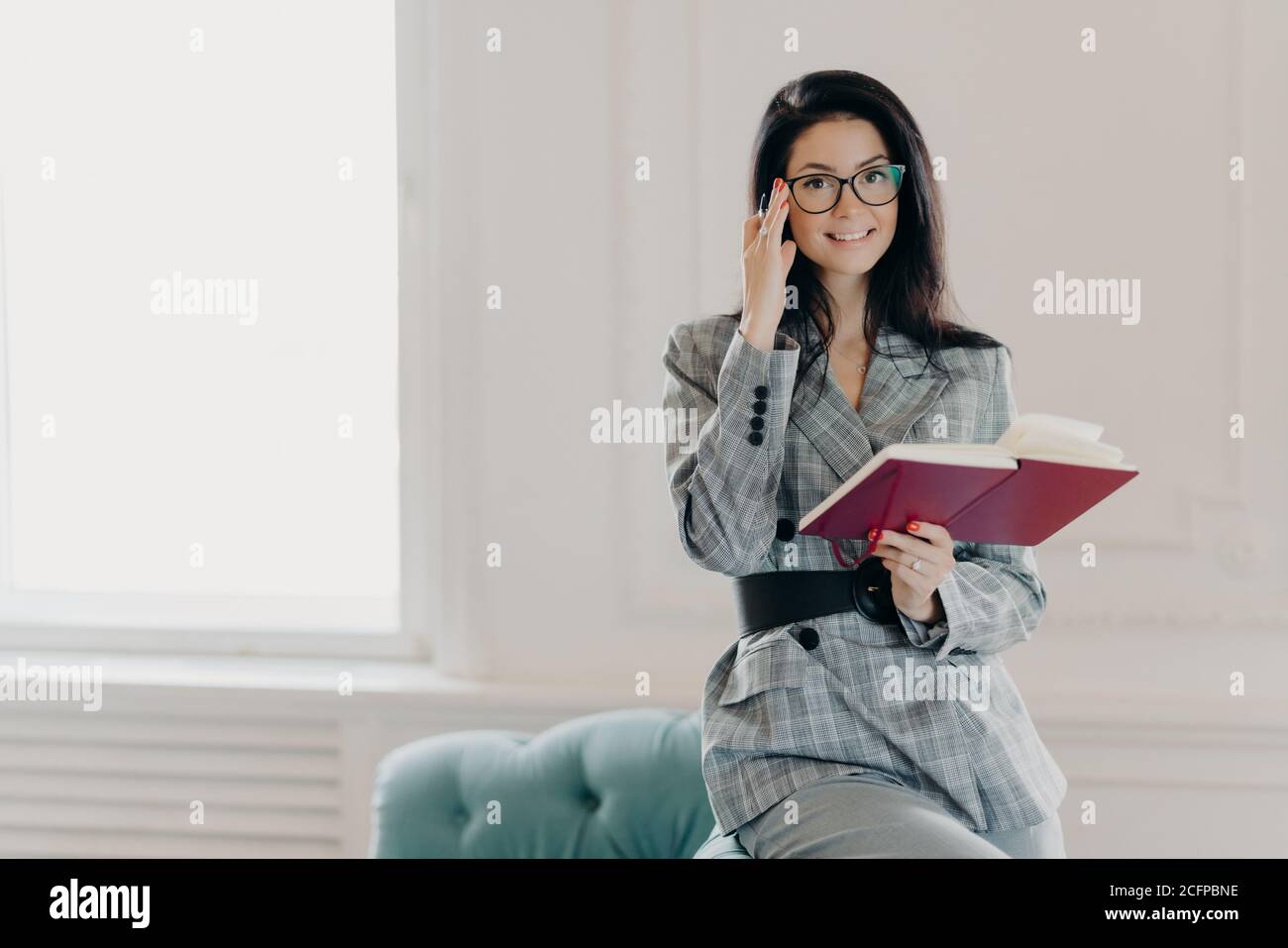 Smiling female business reporter in formal clothes holds opened ...