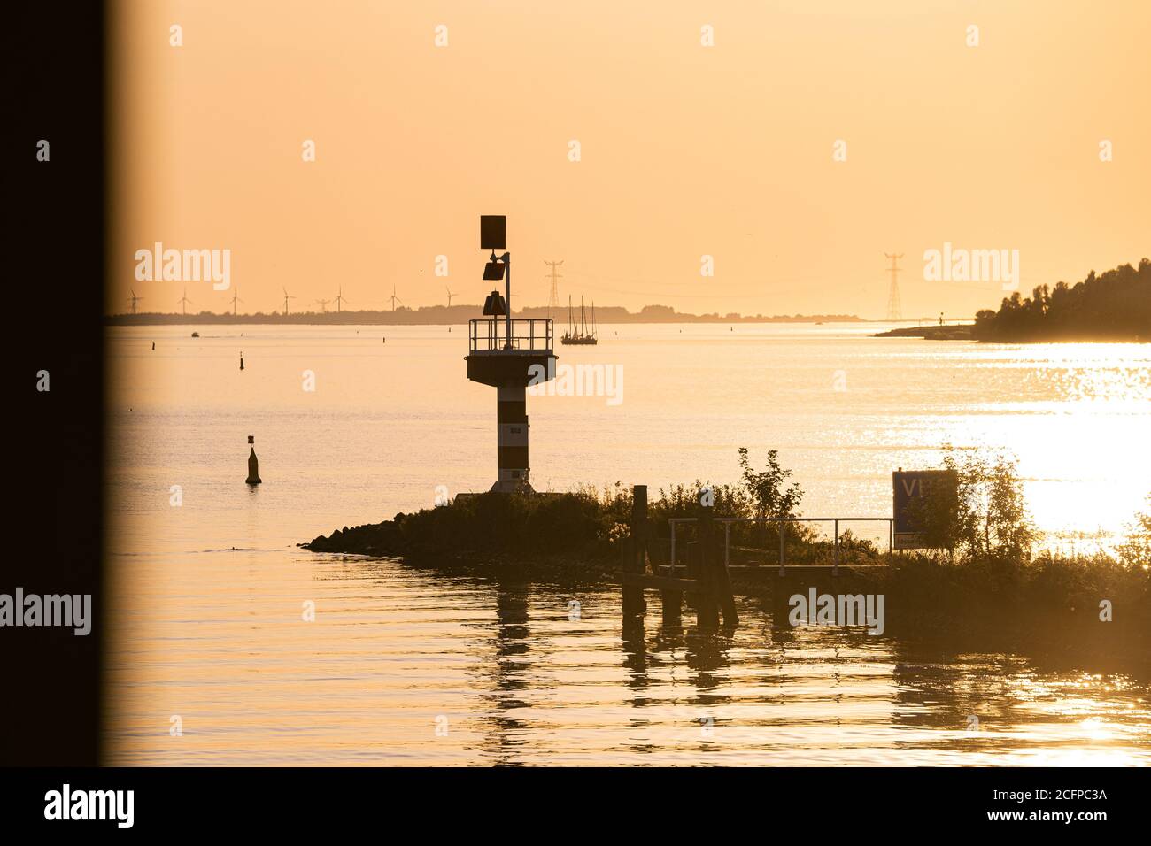 Breakwater with light beacon and reflective water surface Stock Photo ...