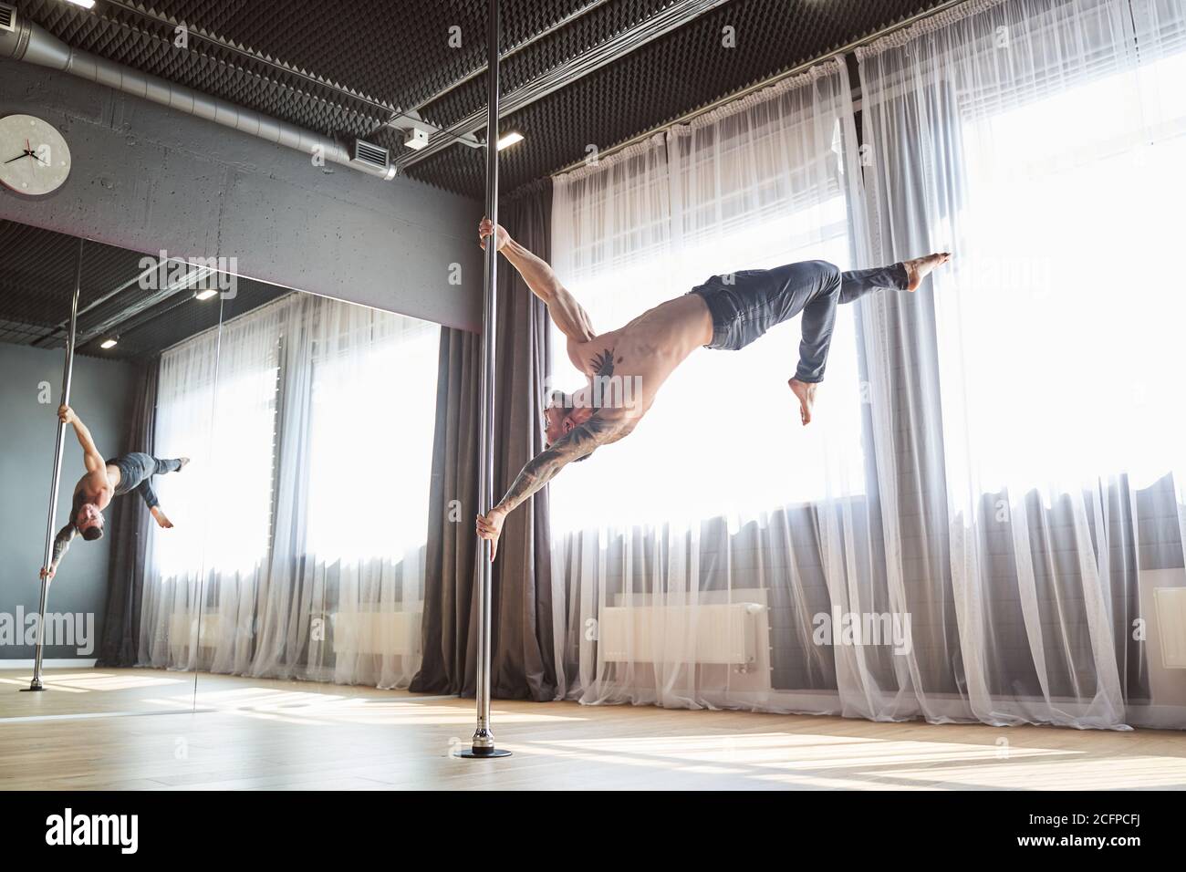 Man athlete performing exercises on the pole on the stage Stock Photo ...