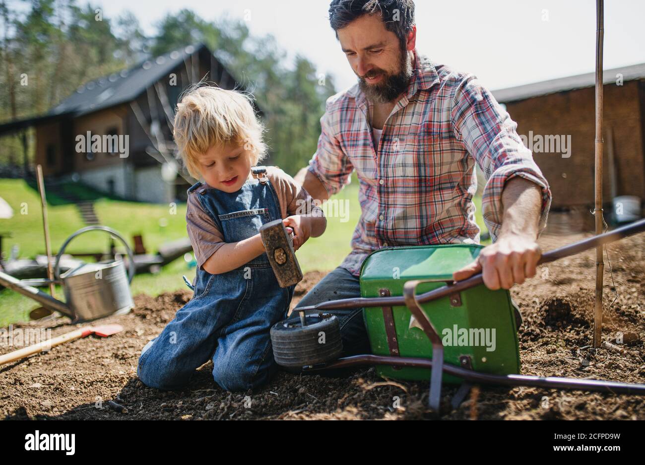 Father with small son working outdoors in garden, sustainable lifestyle ...