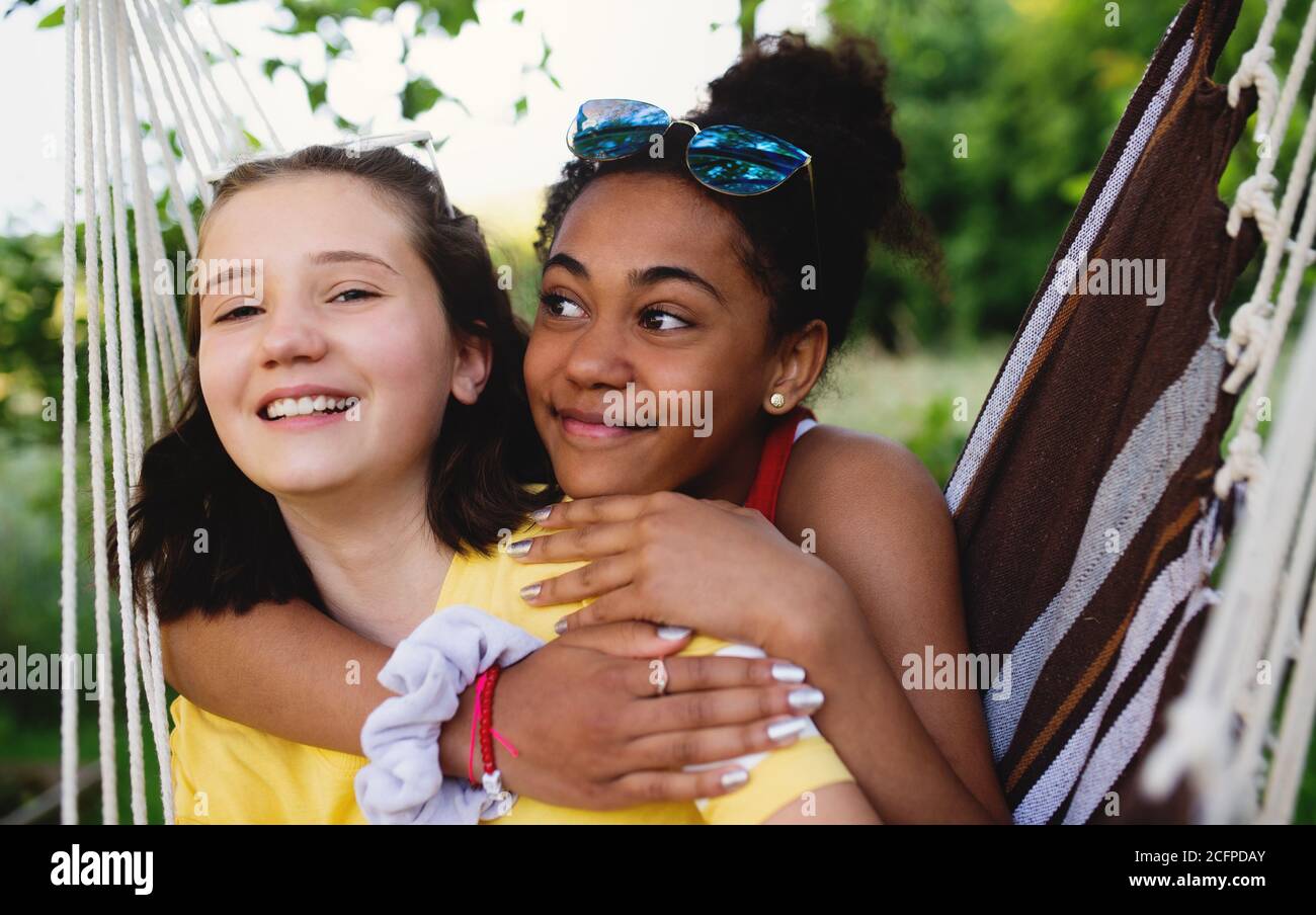 Front view of young teenager girls friends outdoors in garden, resting ...
