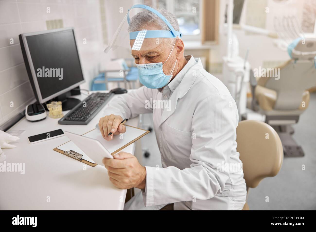 Focused elderly medic checking data on his tablet Stock Photo - Alamy