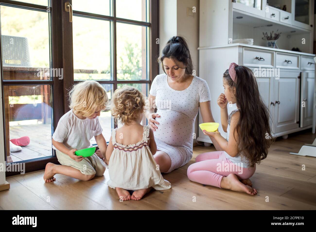 Pregnant woman with small children indoors at home, talking Stock Photo ...