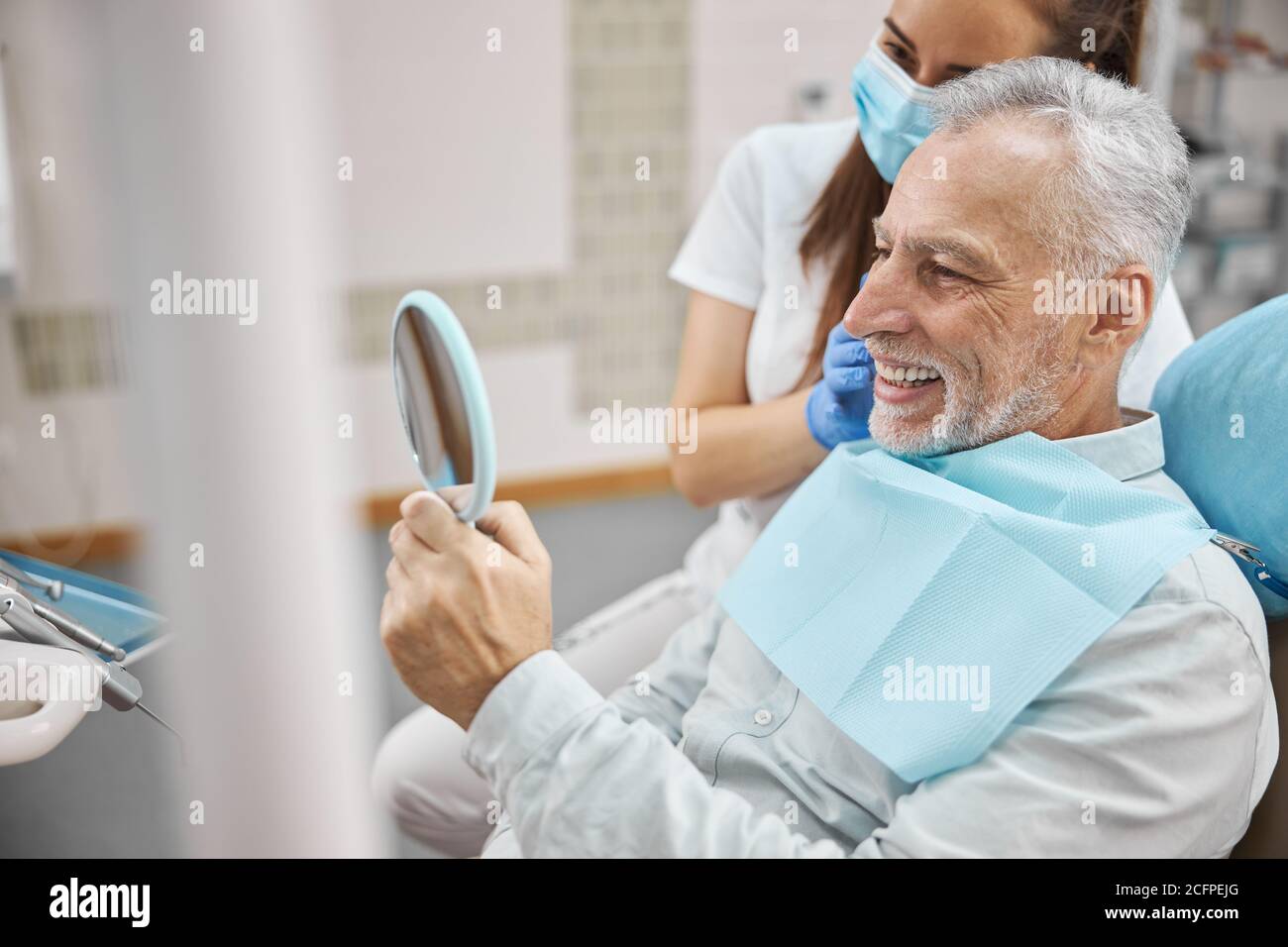 Aging patient looking in the mirror in dental office Stock Photo - Alamy