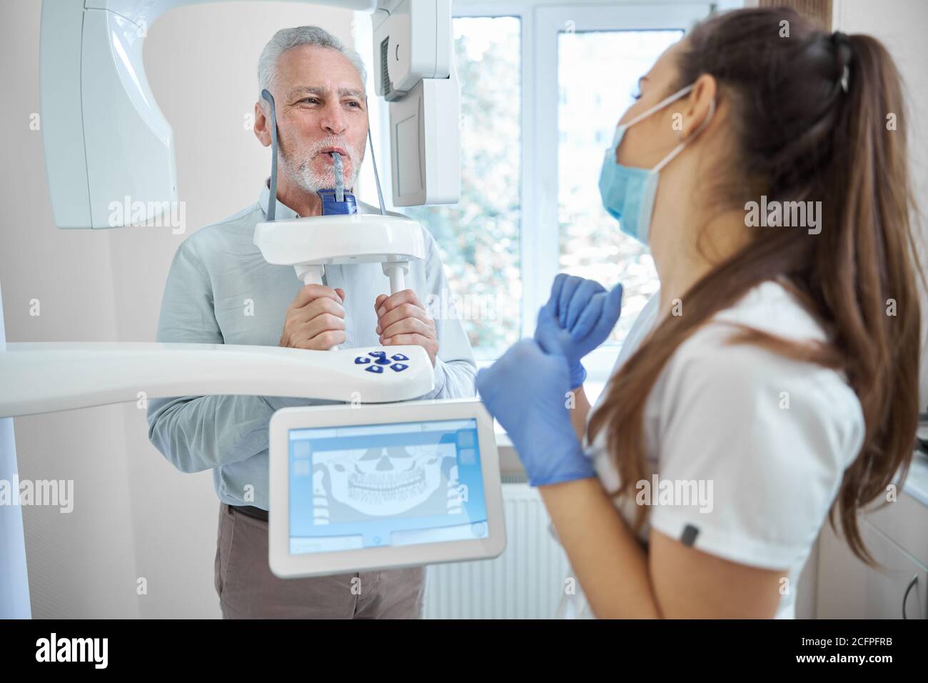 Professional dentist looking at her patient getting x-ray Stock Photo ...