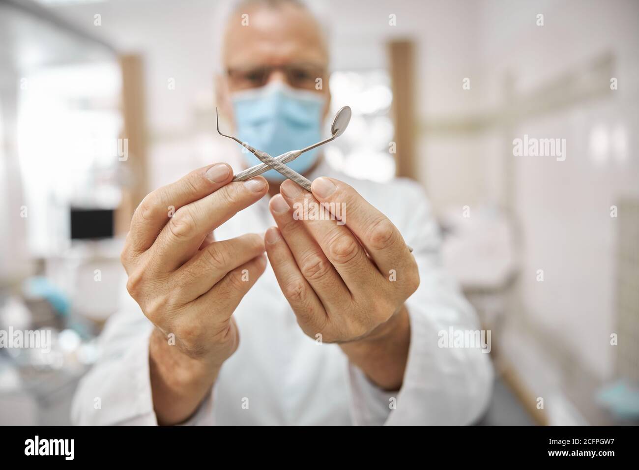 Professional dentist holding his dental tools crossed Stock Photo - Alamy