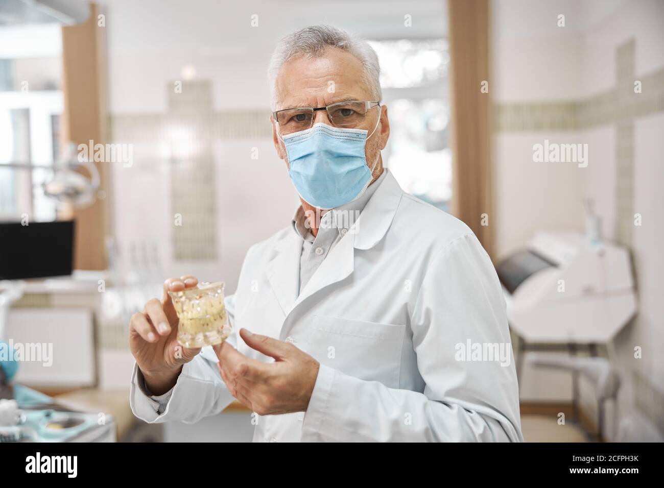 Elderly dental expert holding a full jaws dental implant Stock Photo ...