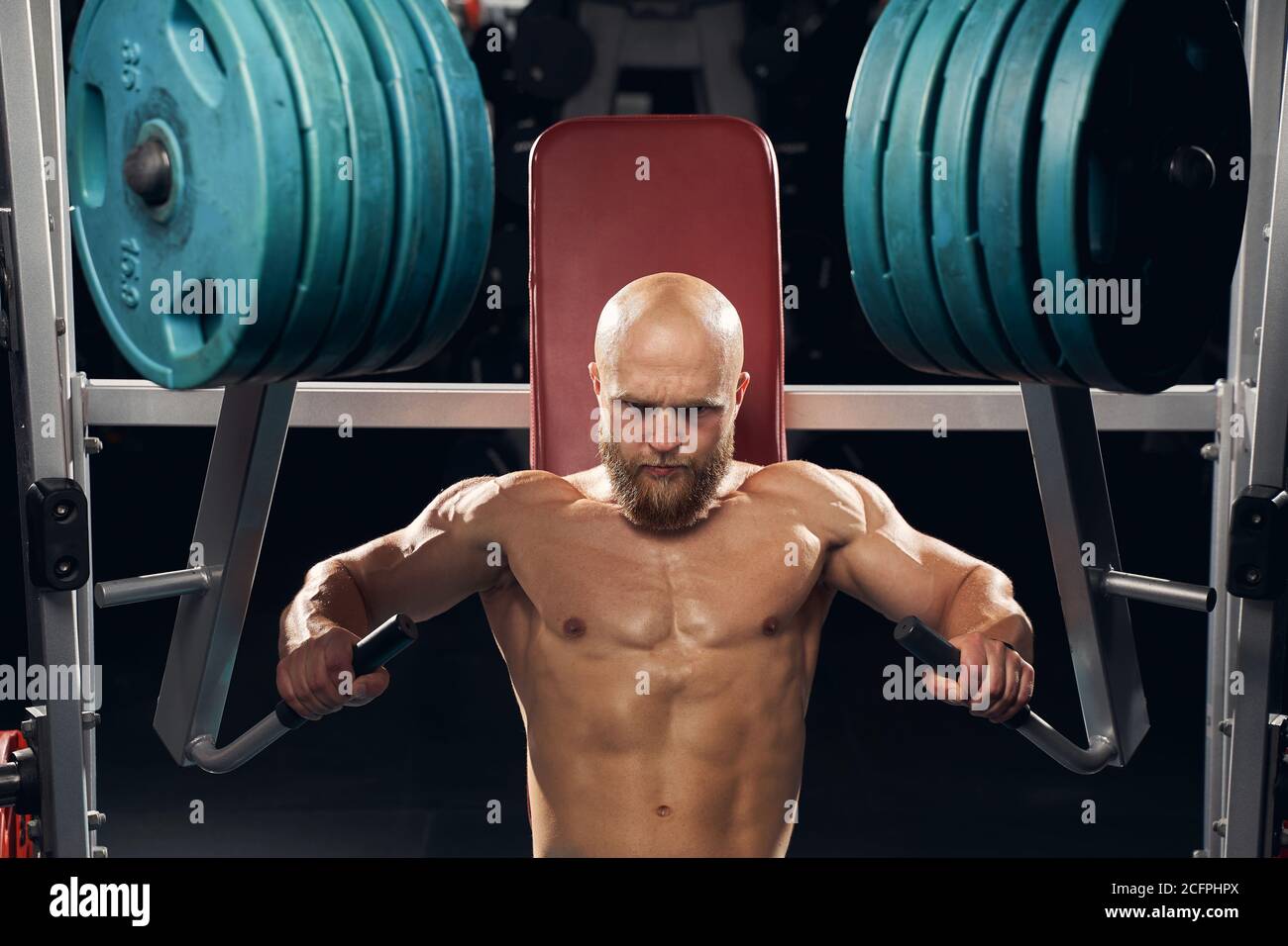 Muscled man using a chest press machine at gym Stock Photo - Alamy