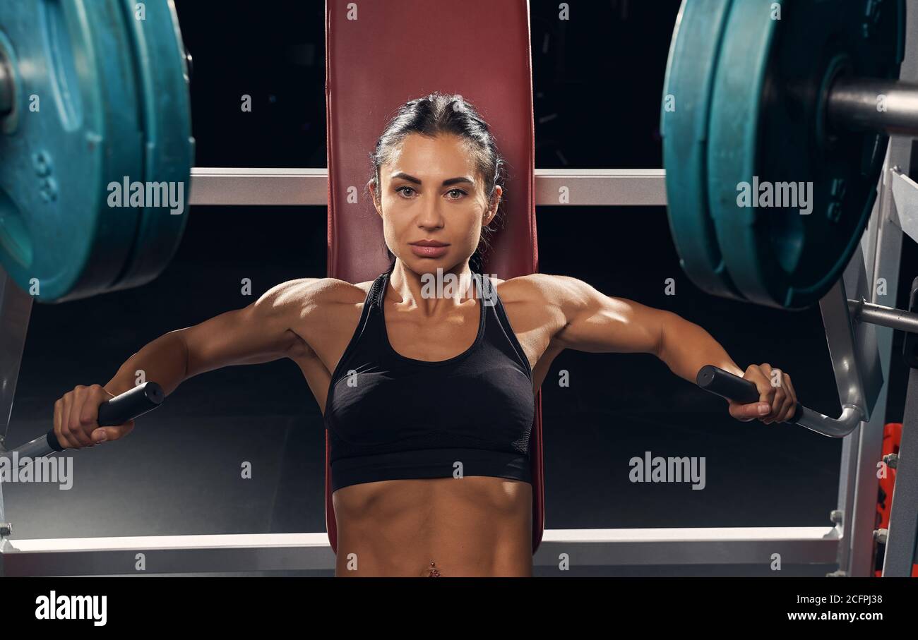 Athletic woman working out on a chest press machine Stock Photo - Alamy
