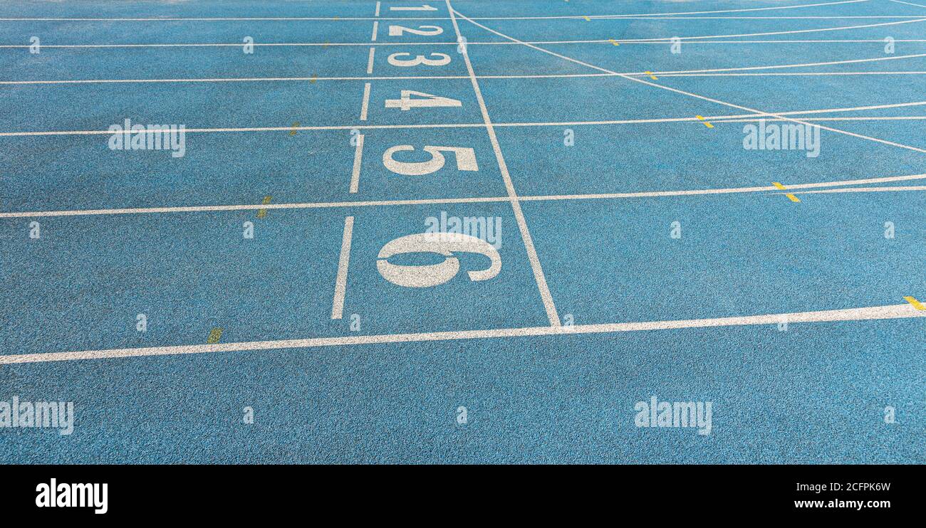 white numbers at the blue running track start line Stock Photo - Alamy