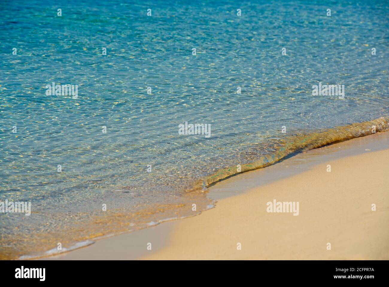 Closeup view across an empty sandy tropical beach shoreline to the open ...