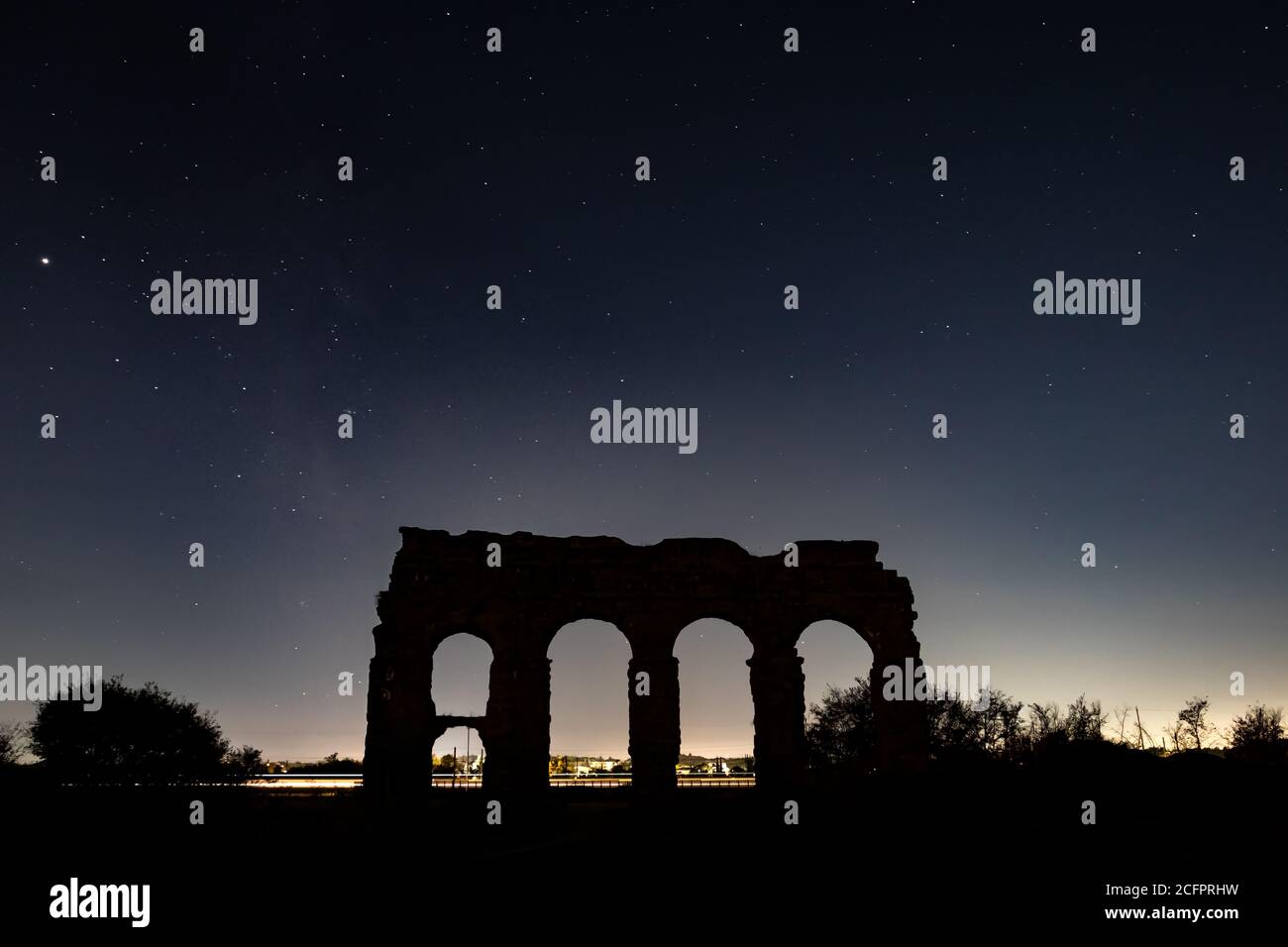 The ruins of an ancient Roman aqueduct at night with starry sky. In the ...