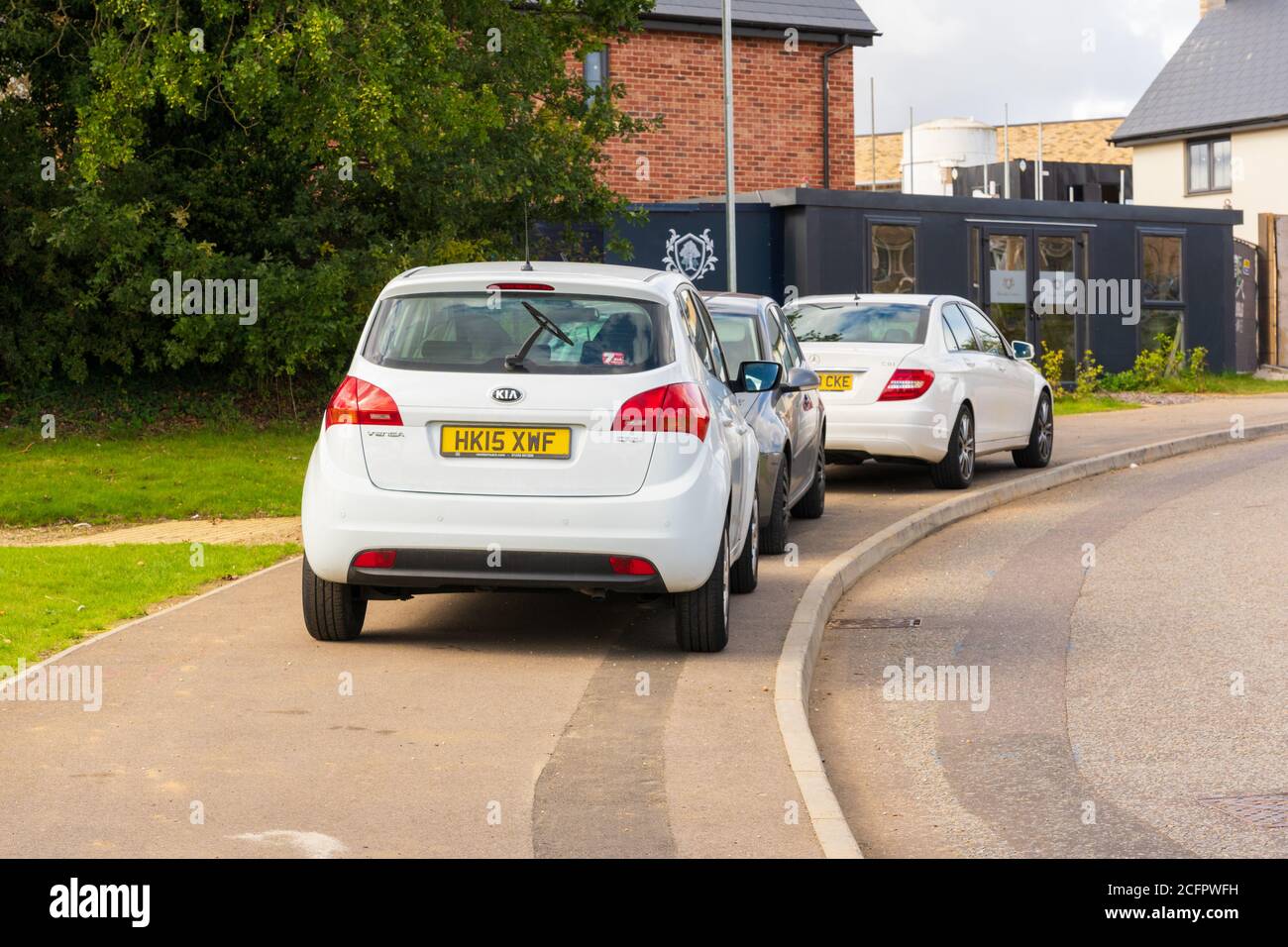 Three cars parked on a pavement partially blocking the path for ...