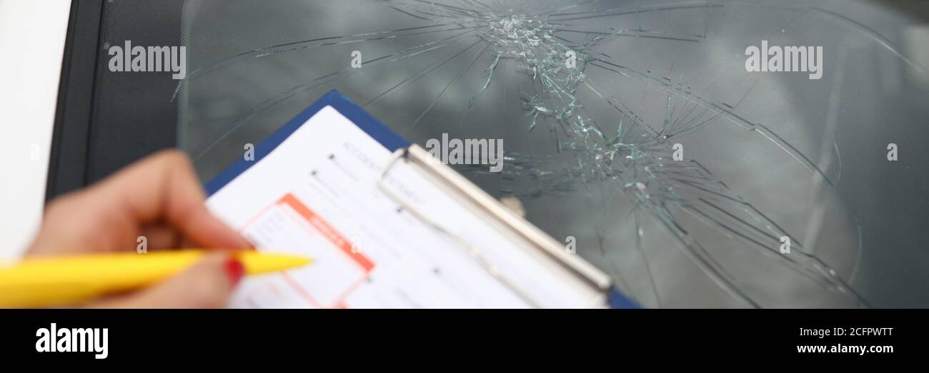 An agent draws up documents for broken windshield in car Stock Photo ...