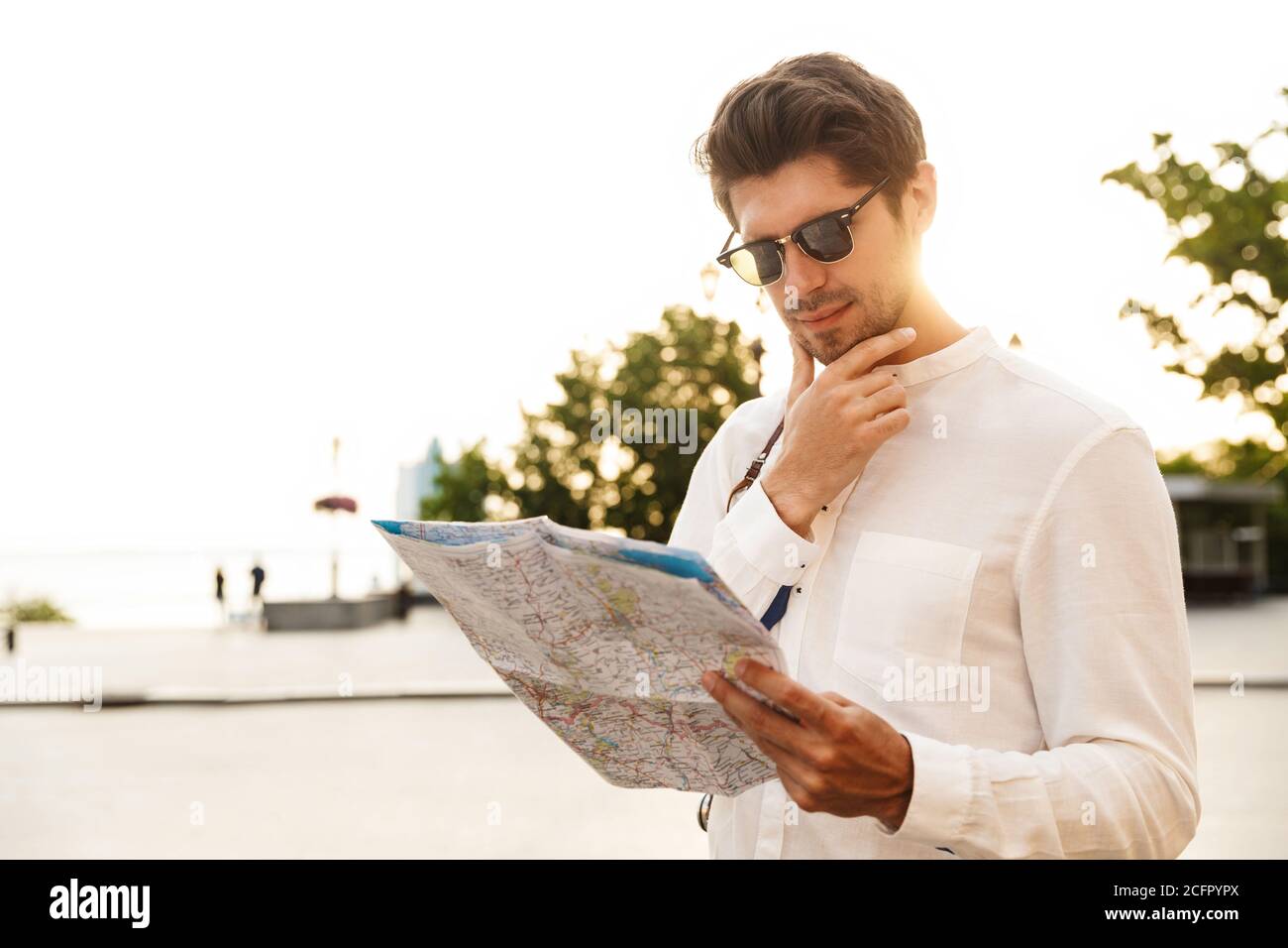 Close up of a handsome happy young stylish man walking outdoors in the ...