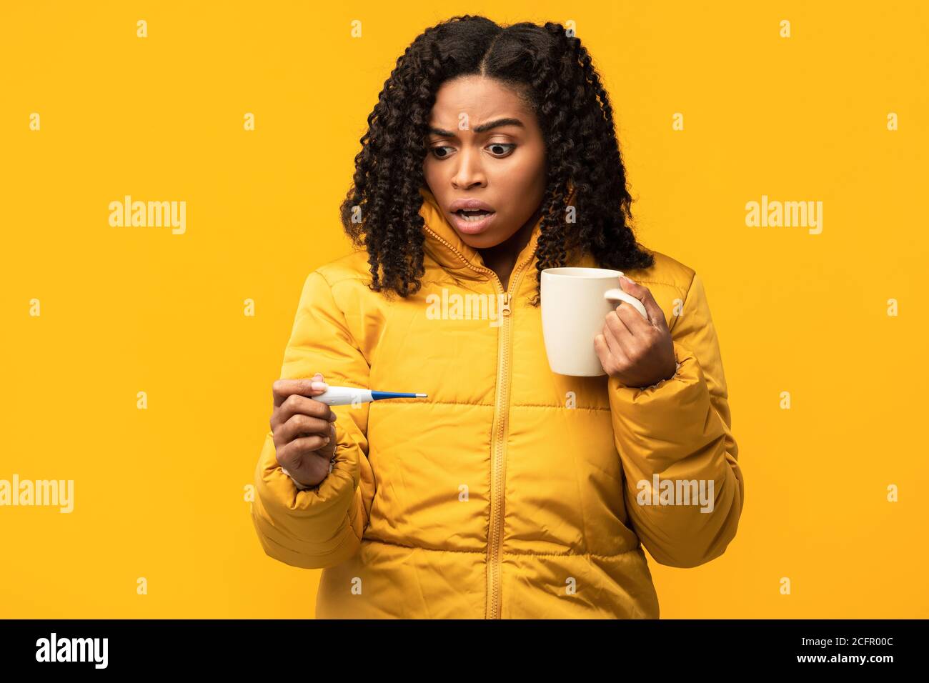 Black Woman In Winter Jacket Holding Thermometer On Yellow Background ...