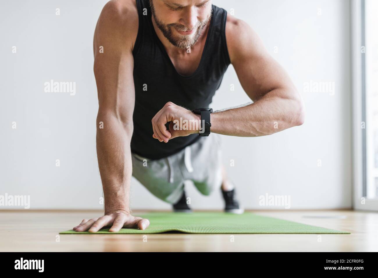 Handsome young man working out at home with a smart watch Stock Photo ...