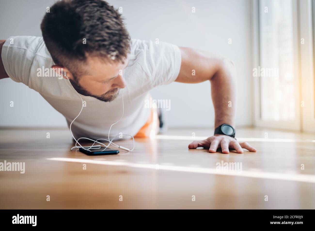 Handsome young man working out at home with a smart watch Stock Photo ...