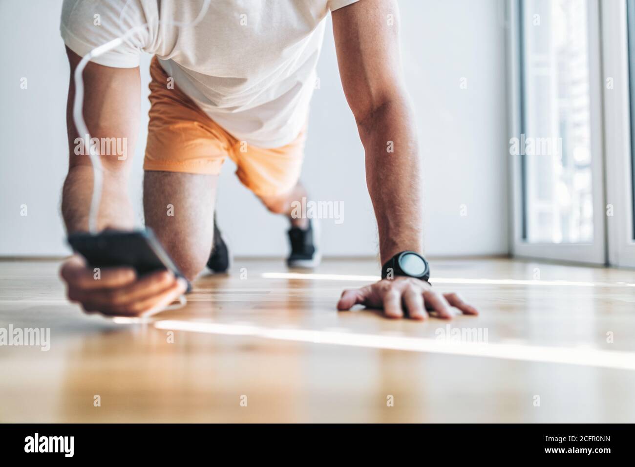 Handsome young man working out at home with a smart watch Stock Photo ...