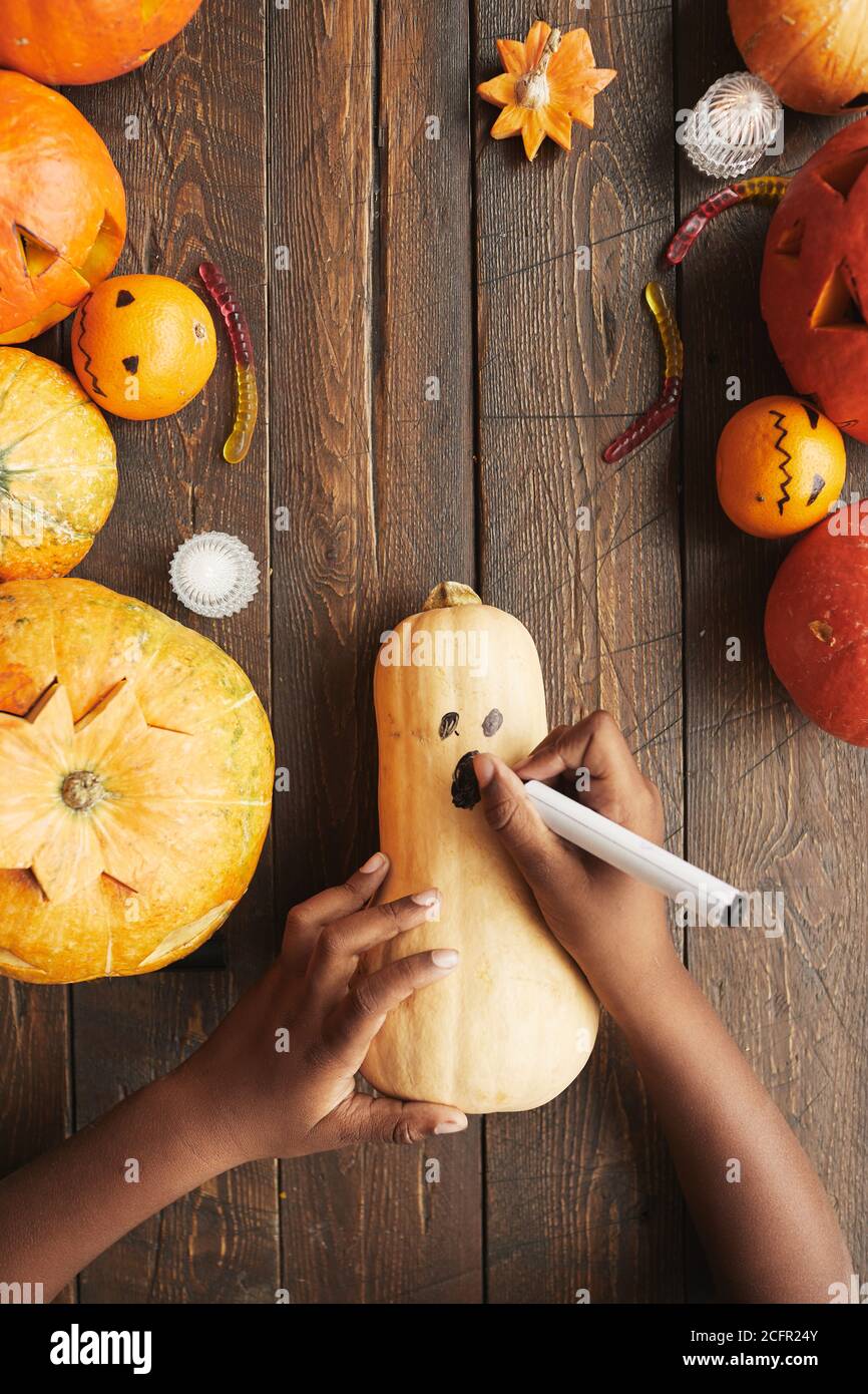 Vertical top-down shot of unrecognizable person drawing scary face on ...