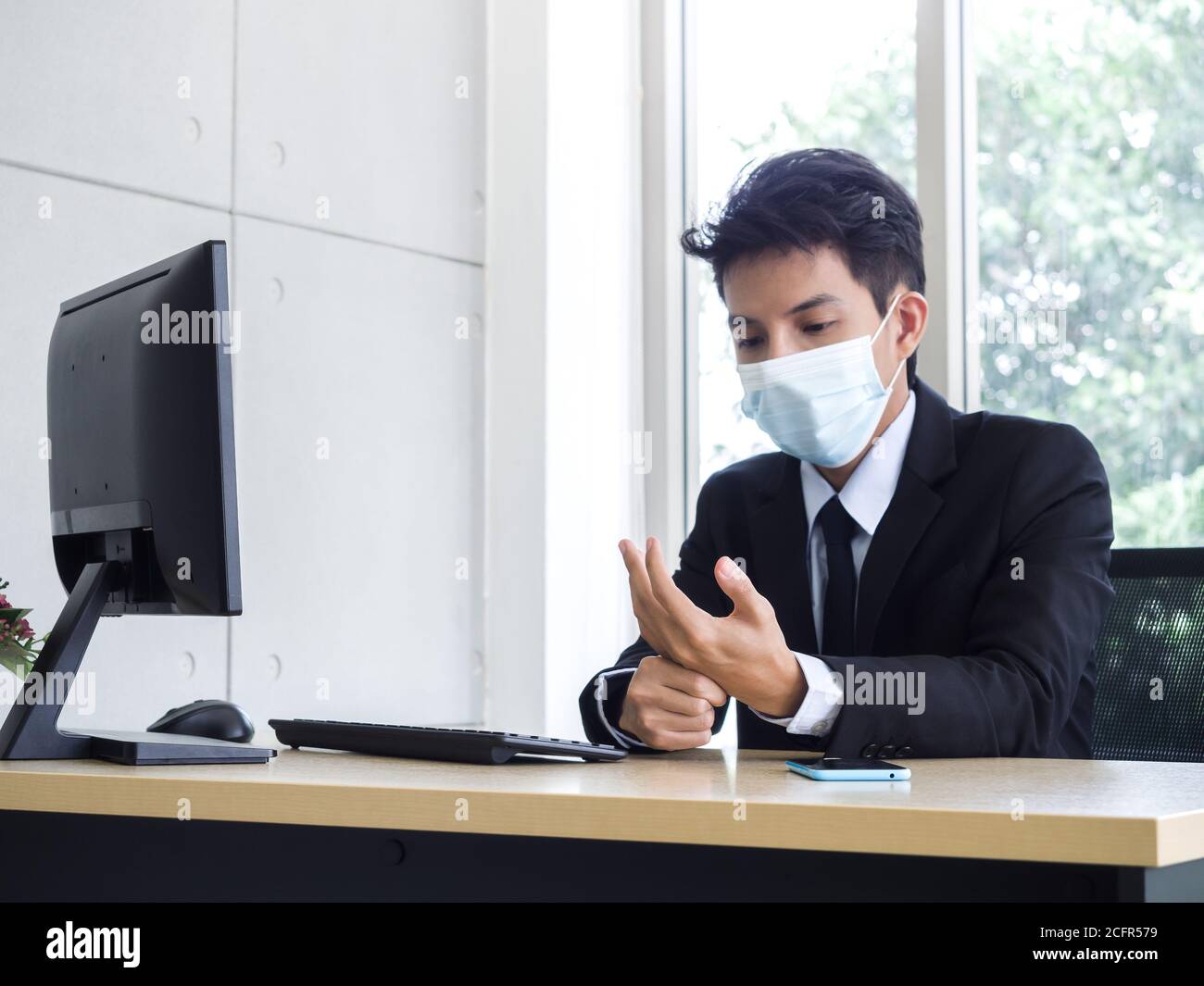 Young Asian businessman in suit wearing medical face mask getting hand ...