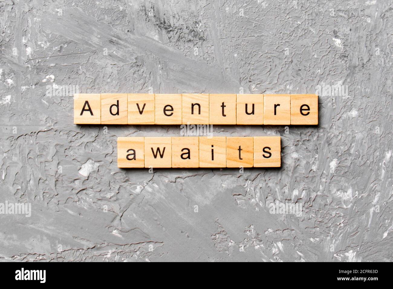 Adventure awaits word written on wood block. Adventure awaits text on ...