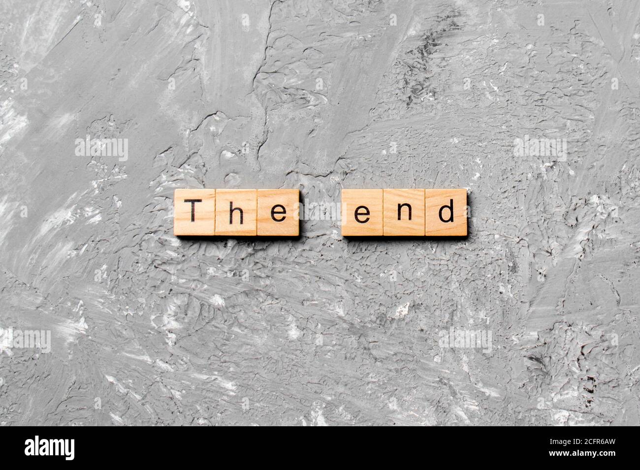 The end word written on wood block. The end text on cement table for ...