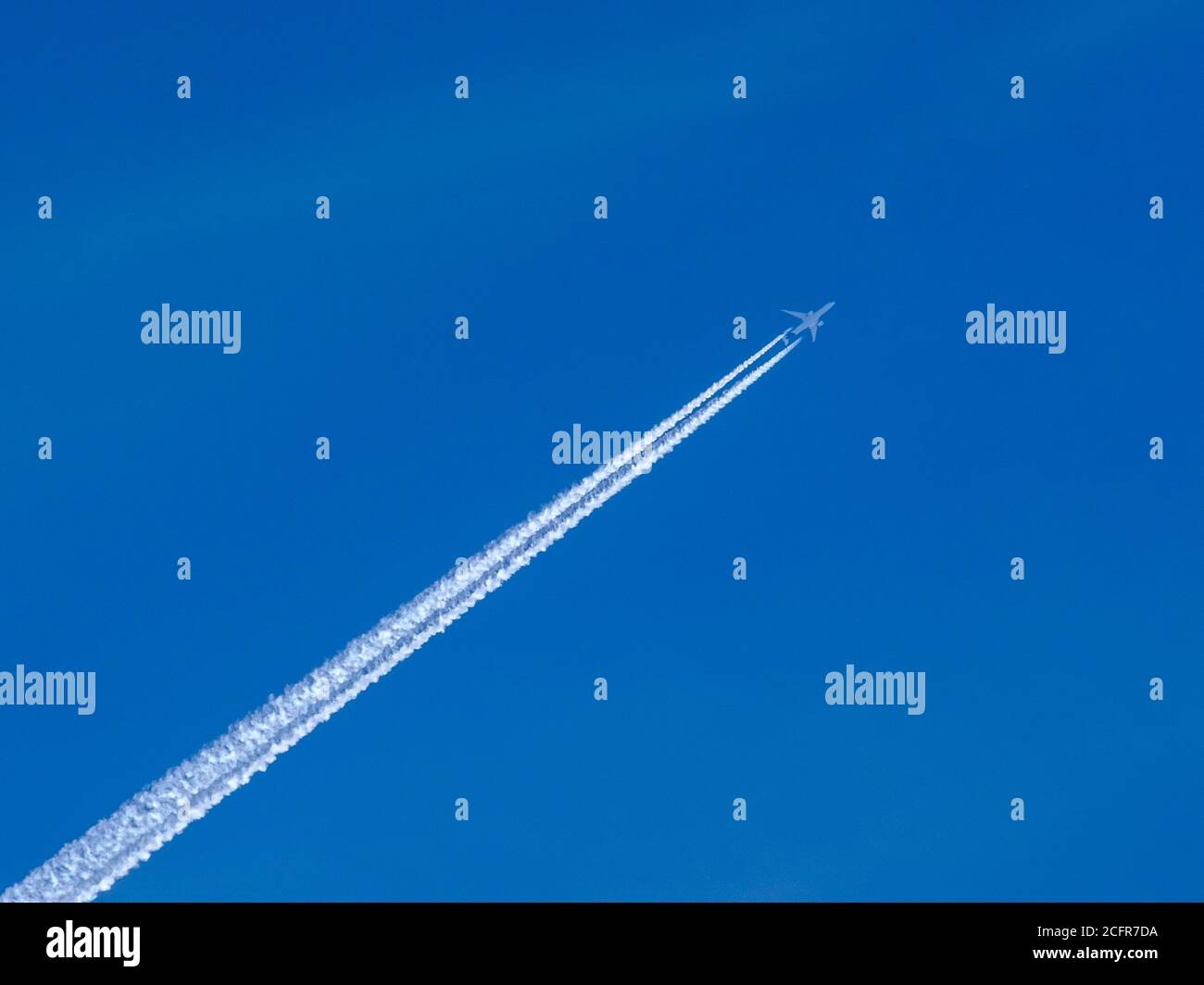 White jet passenger plane flying at high altitude in a blue clear ...