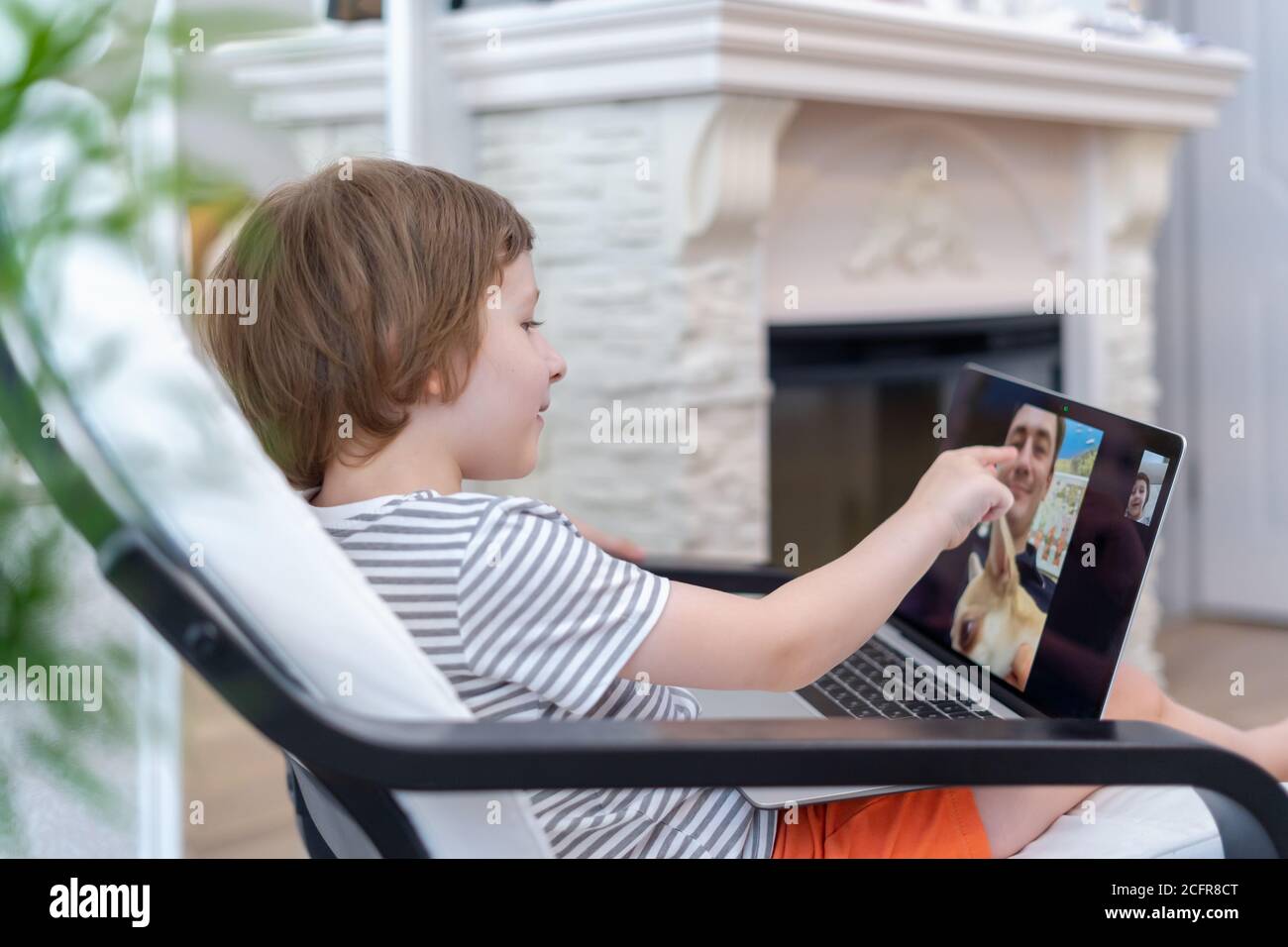 Happy kid boy sit on chair with computer using laptop having a video ...