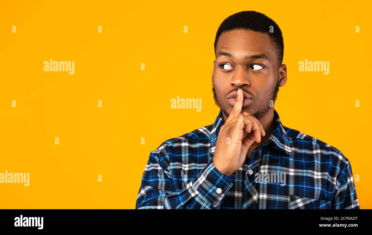 Black Guy Putting Finger On Lips Posing Over Yellow Background Stock ...