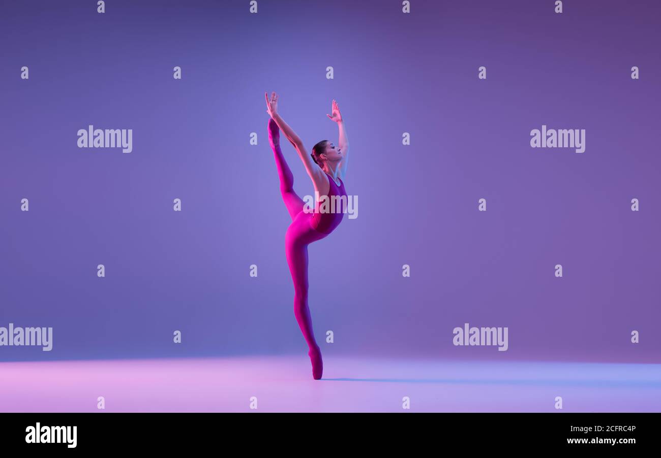 Freedom. Young and graceful ballet dancer isolated on purple studio ...