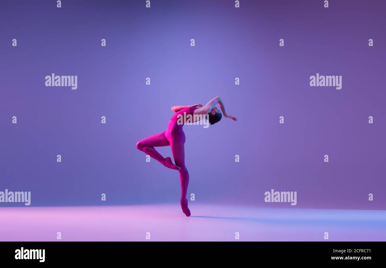 Freedom. Young and graceful ballet dancer isolated on purple studio ...
