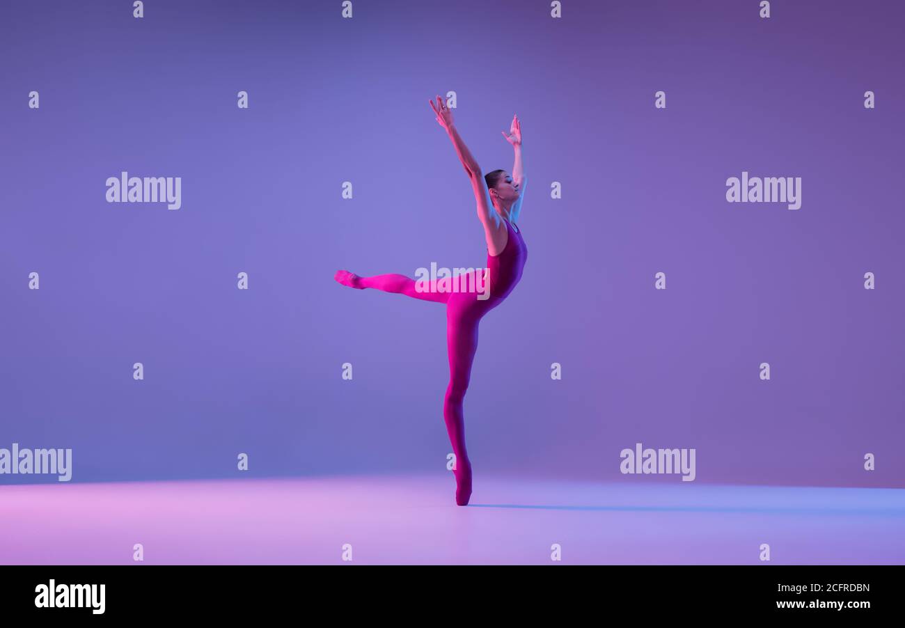 Beautiful. Young and graceful ballet dancer isolated on purple studio ...