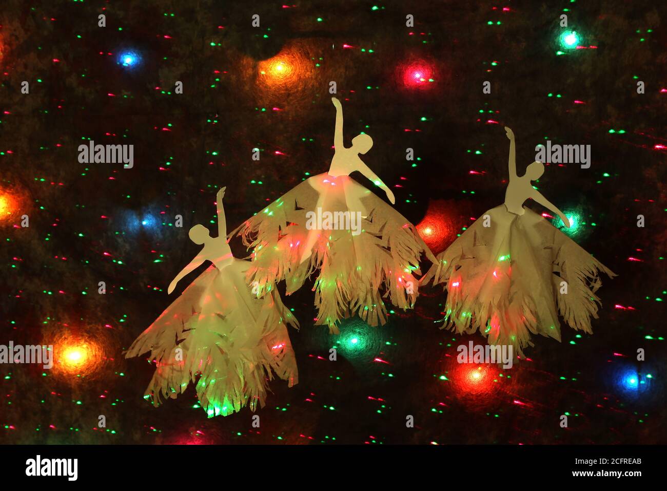 View of three dancing ballerinas made of paper surrounded by colorful ...