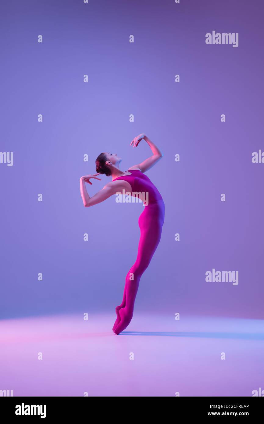 Strong. Young and graceful ballet dancer isolated on purple studio ...