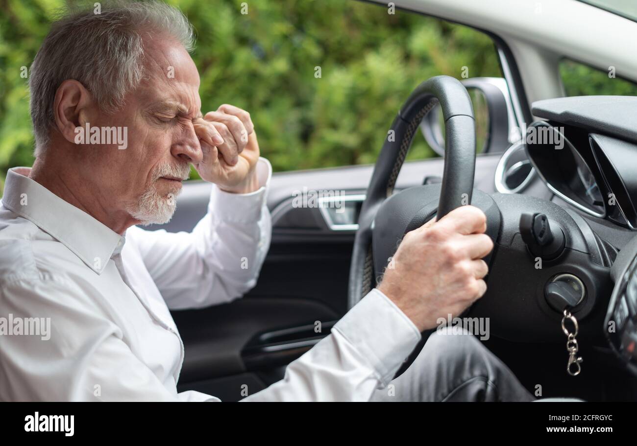 Tired senior man rubbing his eyes behind steering wheel of car Stock ...