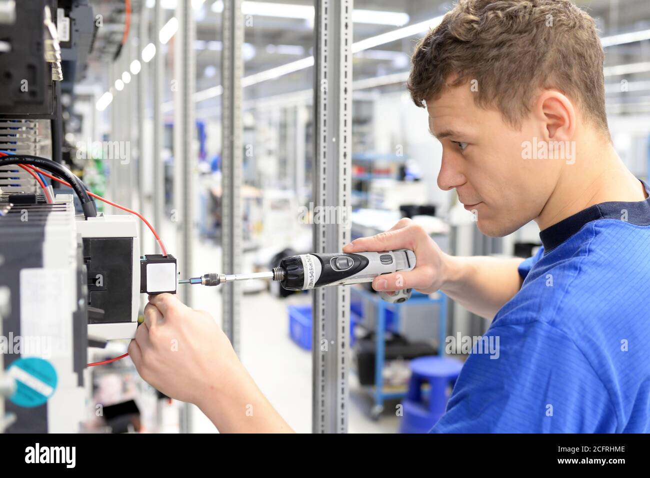 young apprentice worker in an industrial company assembling electronic ...