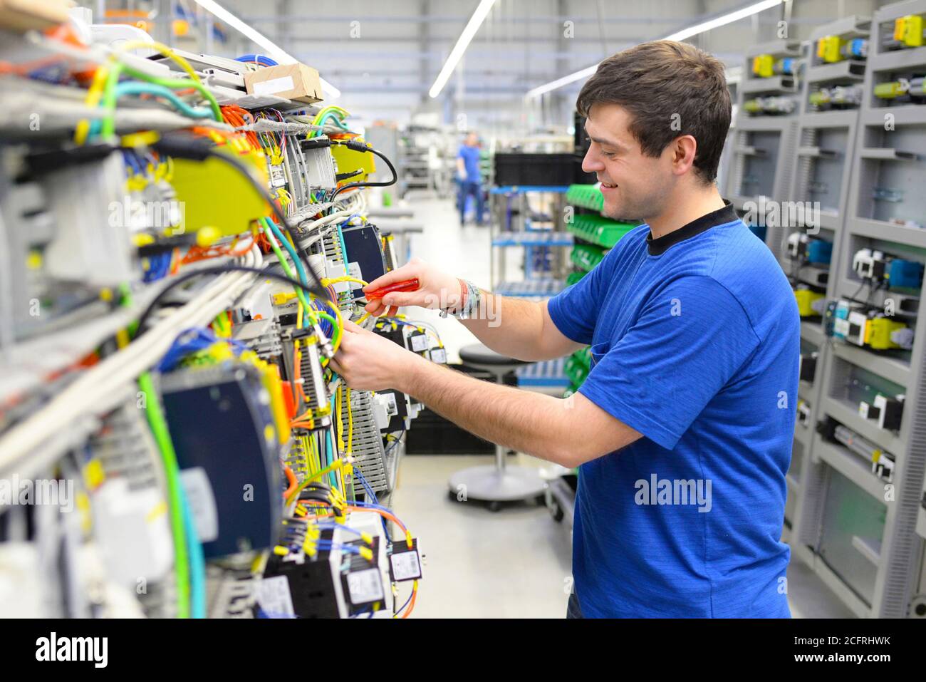 young apprentice assembles components and cables in a factory in a ...