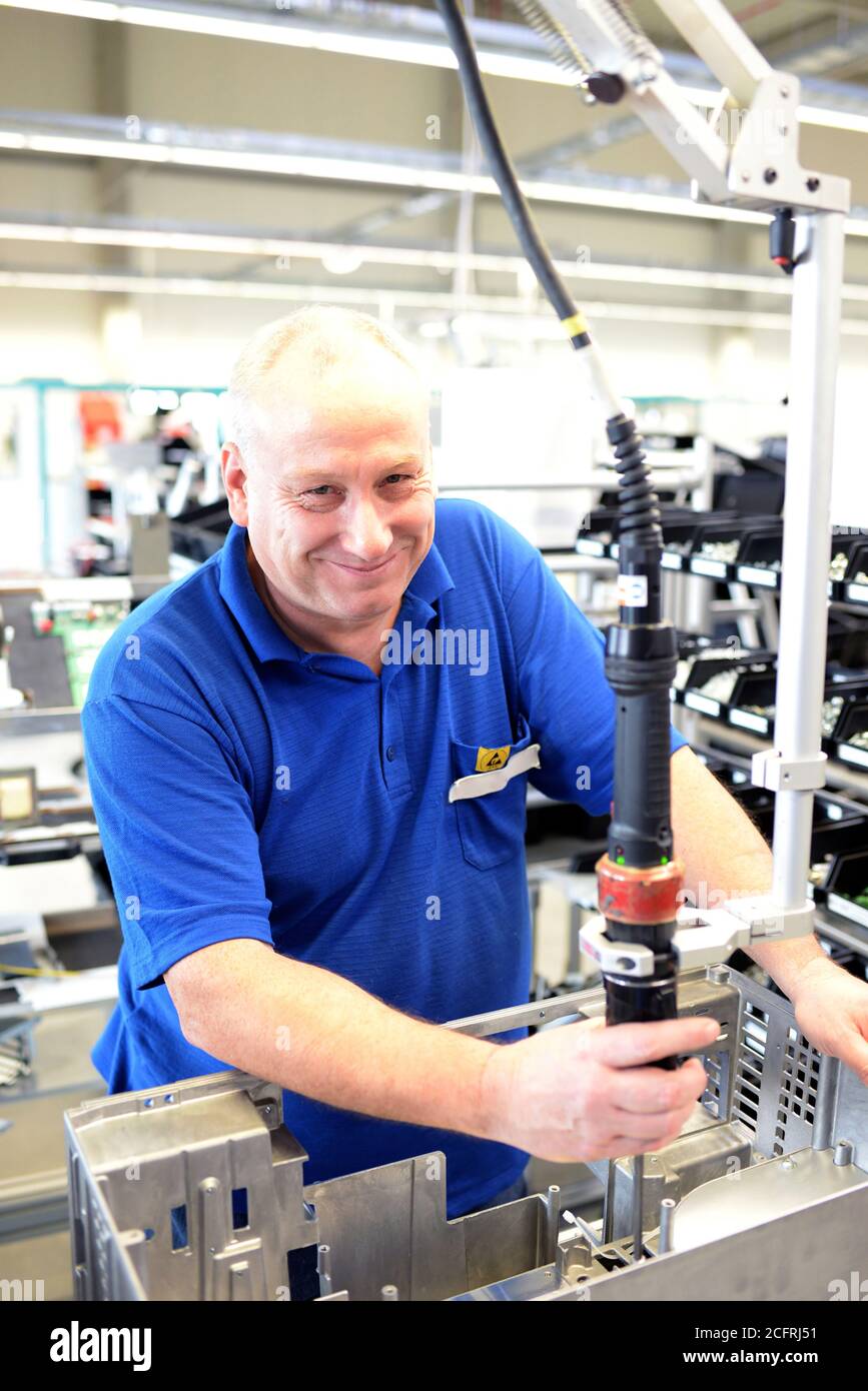 older friendly worker in an industrial company assembles electronic ...