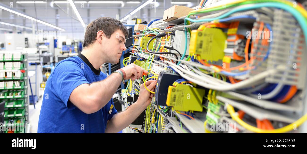 young operator assembles machine in a modern high tech factory ...