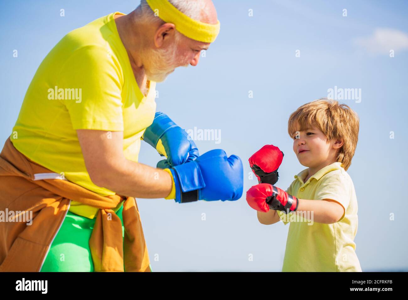 Little boy doing boxing exercise with grandfather. Father is training ...
