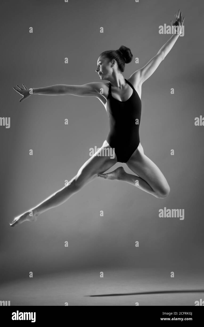 slim latin young woman, ballet dancer, jumping with arms and legs ...